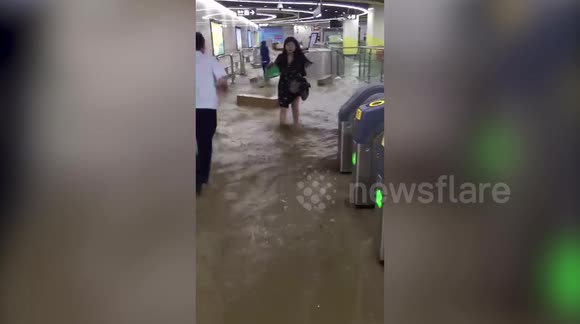 Commuters struggle to walk in flooded metro after heavy rainstorm - Buy ...