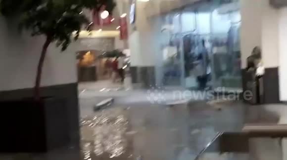 Bemused shoppers walk by 'river' inside flooded mall after roof ...