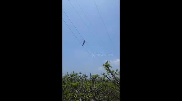 Vietnamese electrical worker swings on high-voltage wires at ...