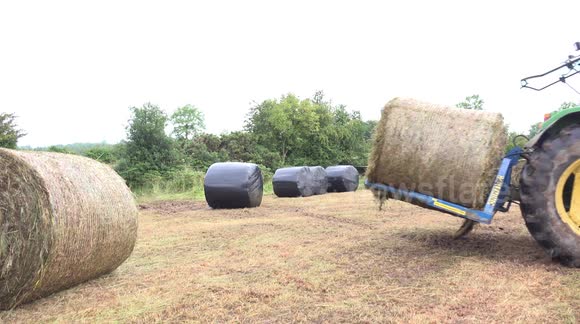 Wrapping bales of hay in black plastic at a farm in rural Ireland ...