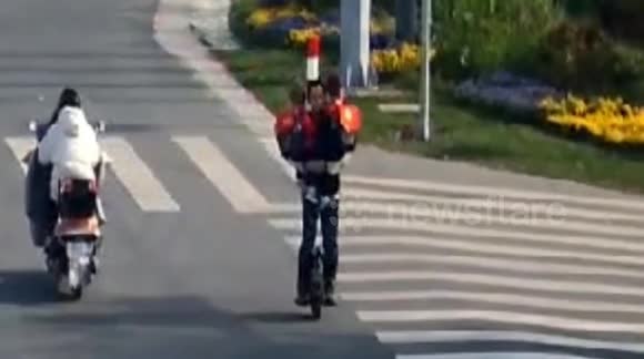 Chinese father rides unicycle while carrying his kids in both hands ...