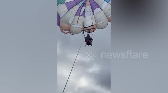 Workaholic tourist types away on laptop while floating on parasail ...