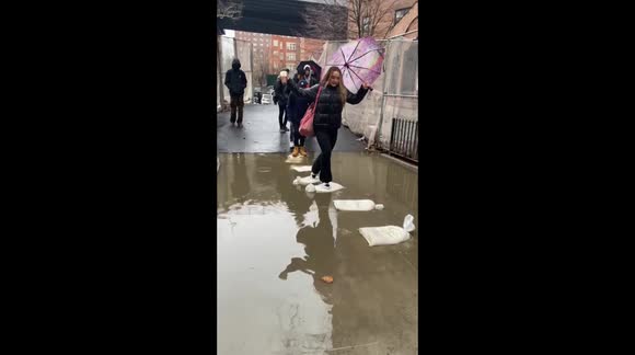 New Yorkers use sandbags to create path across deep puddle on sidewalk ...