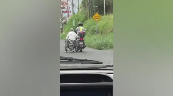 Kind motorcycle rider helps disabled man along road by pulling his ...