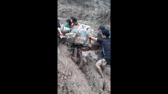 Locals struggle to push motorbike through thick mud caused by floods in ...