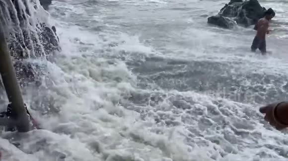 Tourist knocked over by huge wave while posing for pictures on beach ...