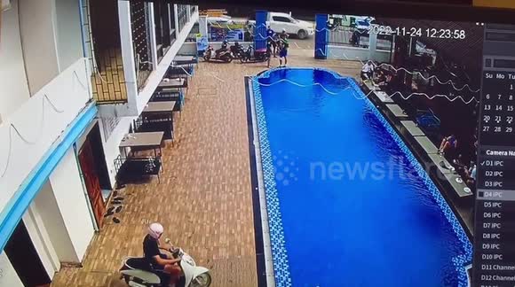 Clumsy backpacker falls into hotel swimming pool while trying to ride ...