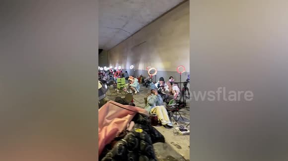 Group of online broadcasters gather under bridge to live stream in ...