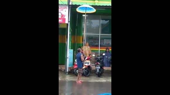 Impressive fail or ingenious hack? Man uses giant umbrella during storm ...