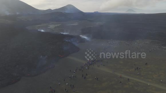 Crowds of people standing and watching lava slowly approach them ...