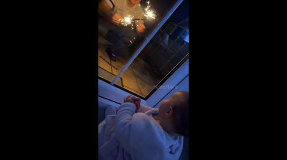 Cute baby is captivated by the enchanting fireworks display in the ...
