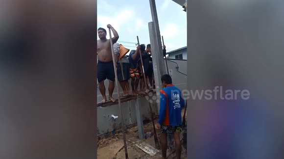 Workers stand on plank to bury it with their weight in construction ...