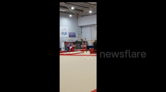 A young male gymnast competes his parallel bar routine. It is going ...