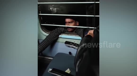 Stowaway clinging to moving train tries reaching inside for valuable ...