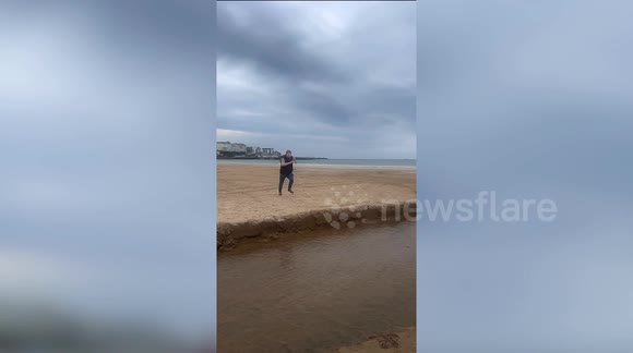 Funny moment man falls short attempting to jump across beach trench and ...