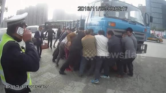 A group of people lift up lorry to rescue two people trapped under it ...